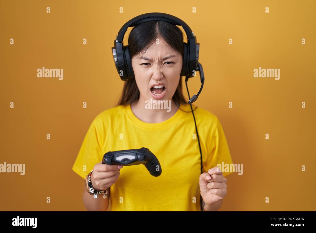 Chinese young woman playing video game holding controller angry and mad ...