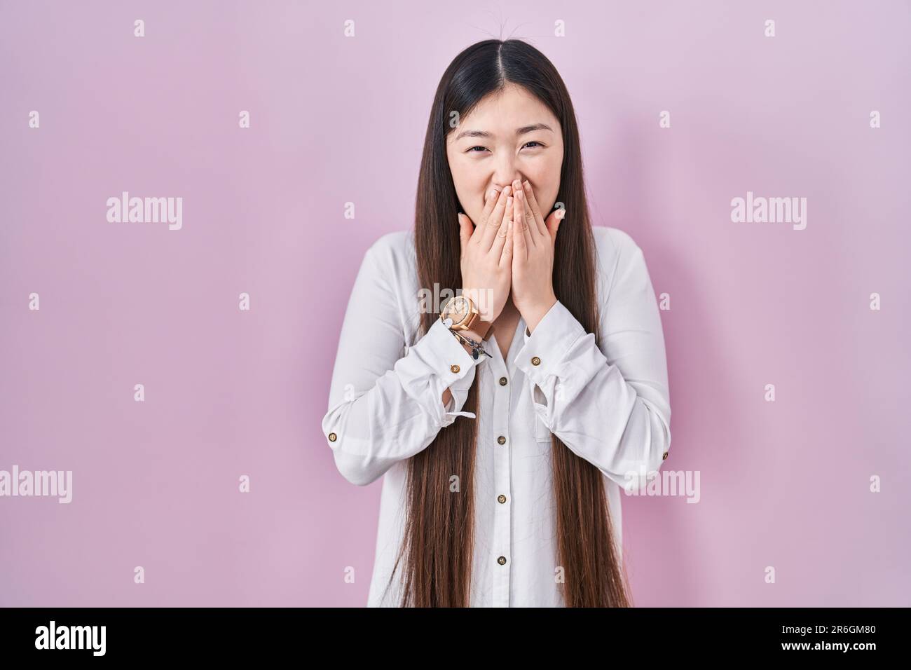 Chinese young woman standing over pink background laughing and ...