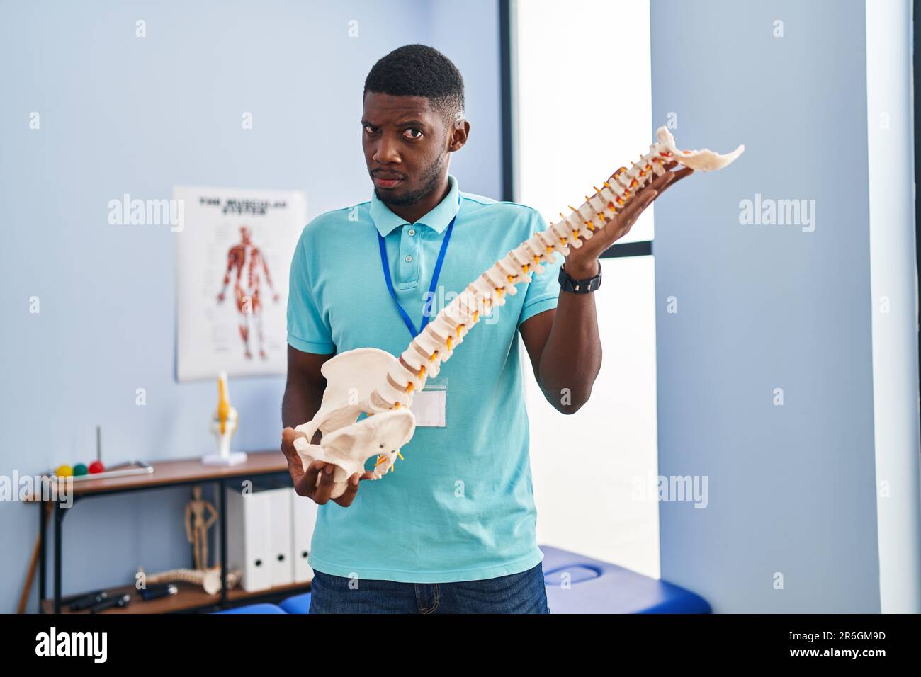 African american man holding anatomical model of spinal column skeptic ...