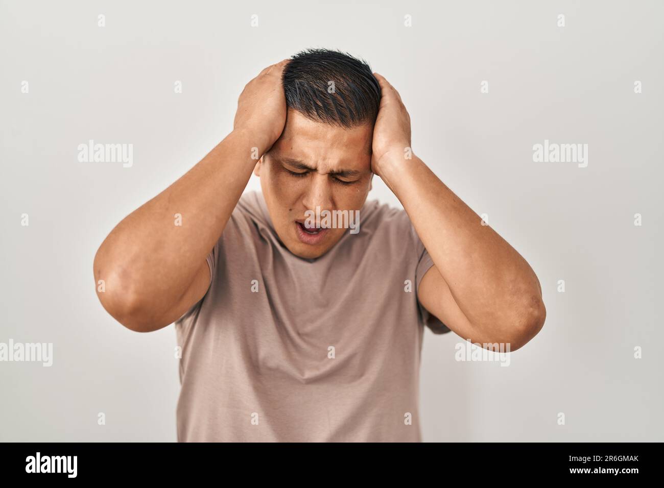 Hispanic young man standing over white background suffering from ...
