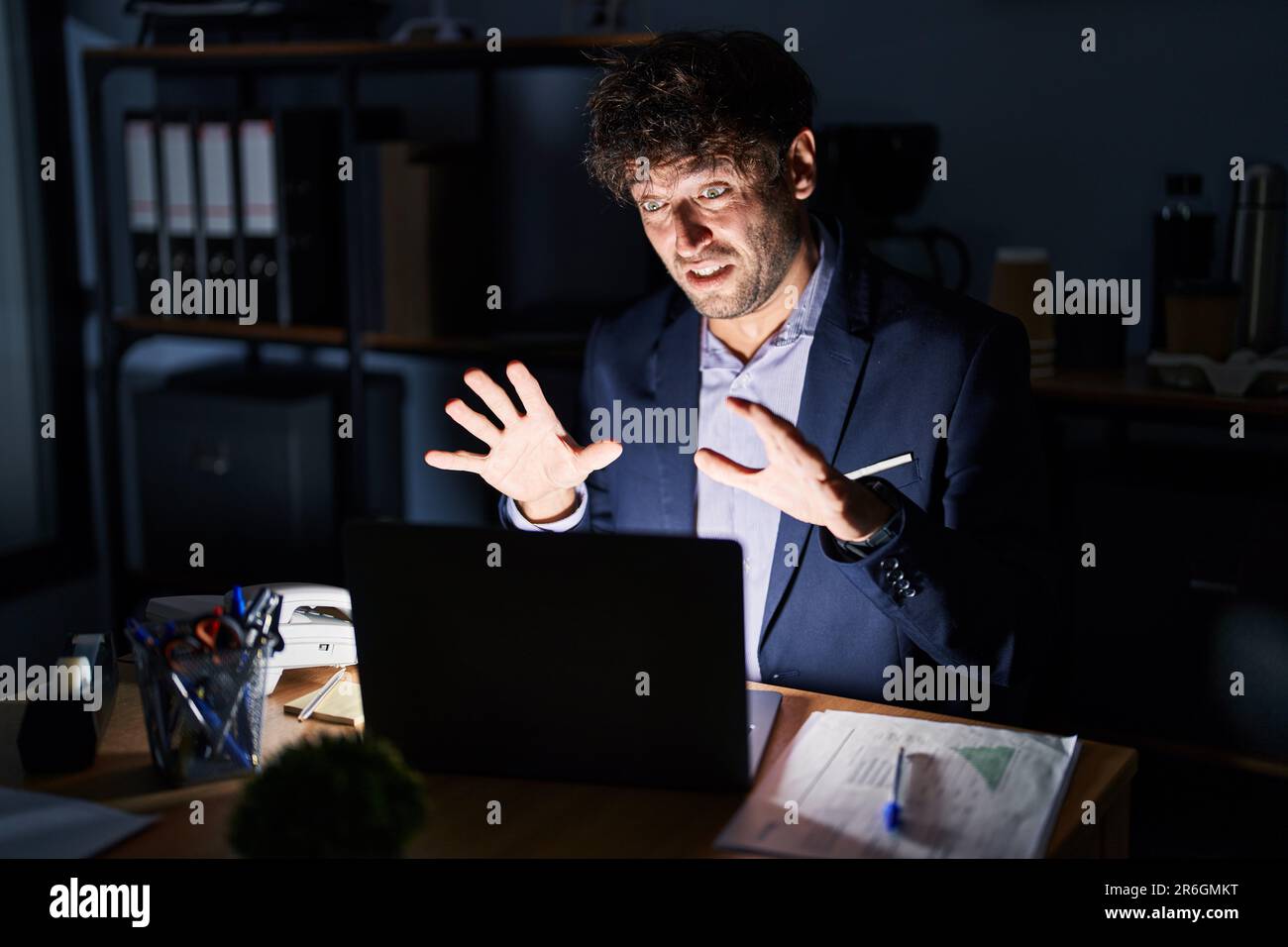 Hispanic young man working at the office at night afraid and terrified ...