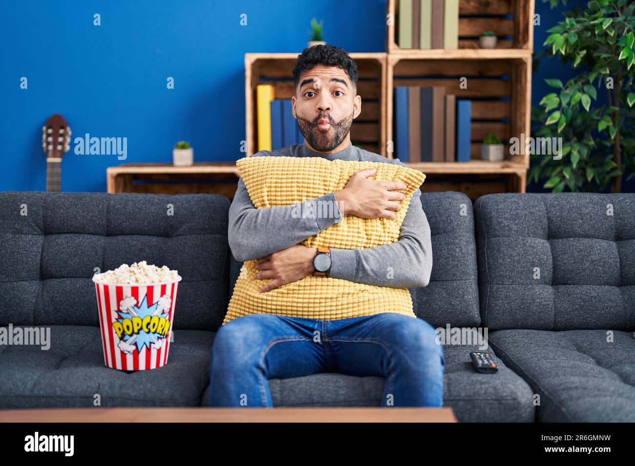 Hispanic man with beard eating popcorn watching a movie at home making ...