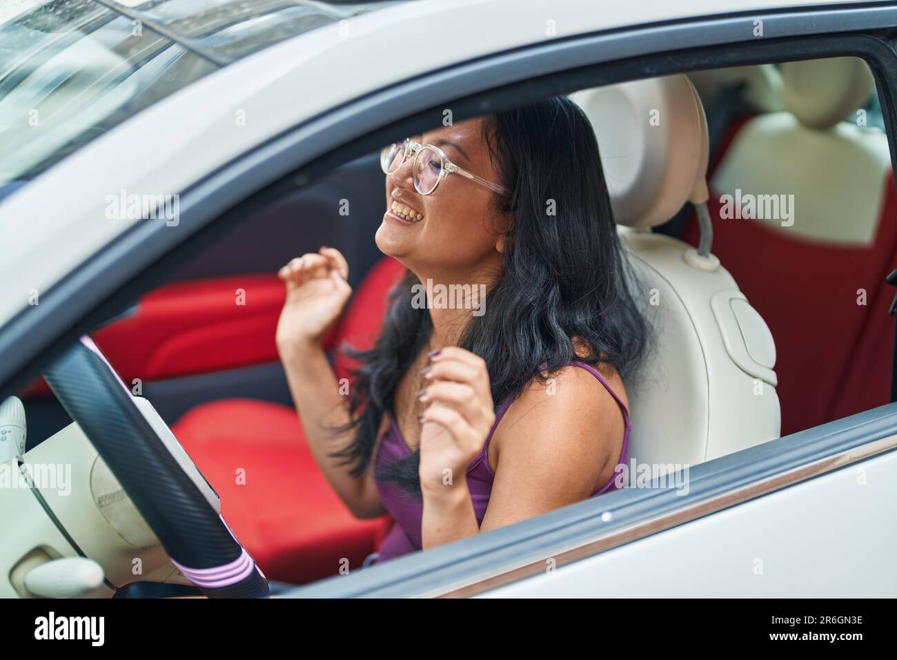 Young chinese woman sitting on car dancing at street Stock Photo - Alamy