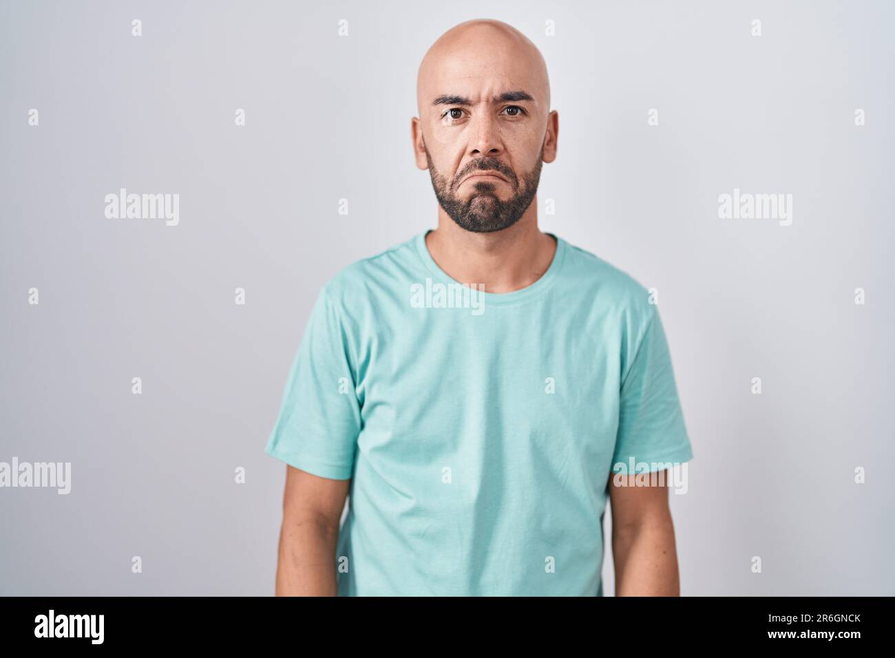 Middle age bald man standing over white background depressed and worry ...
