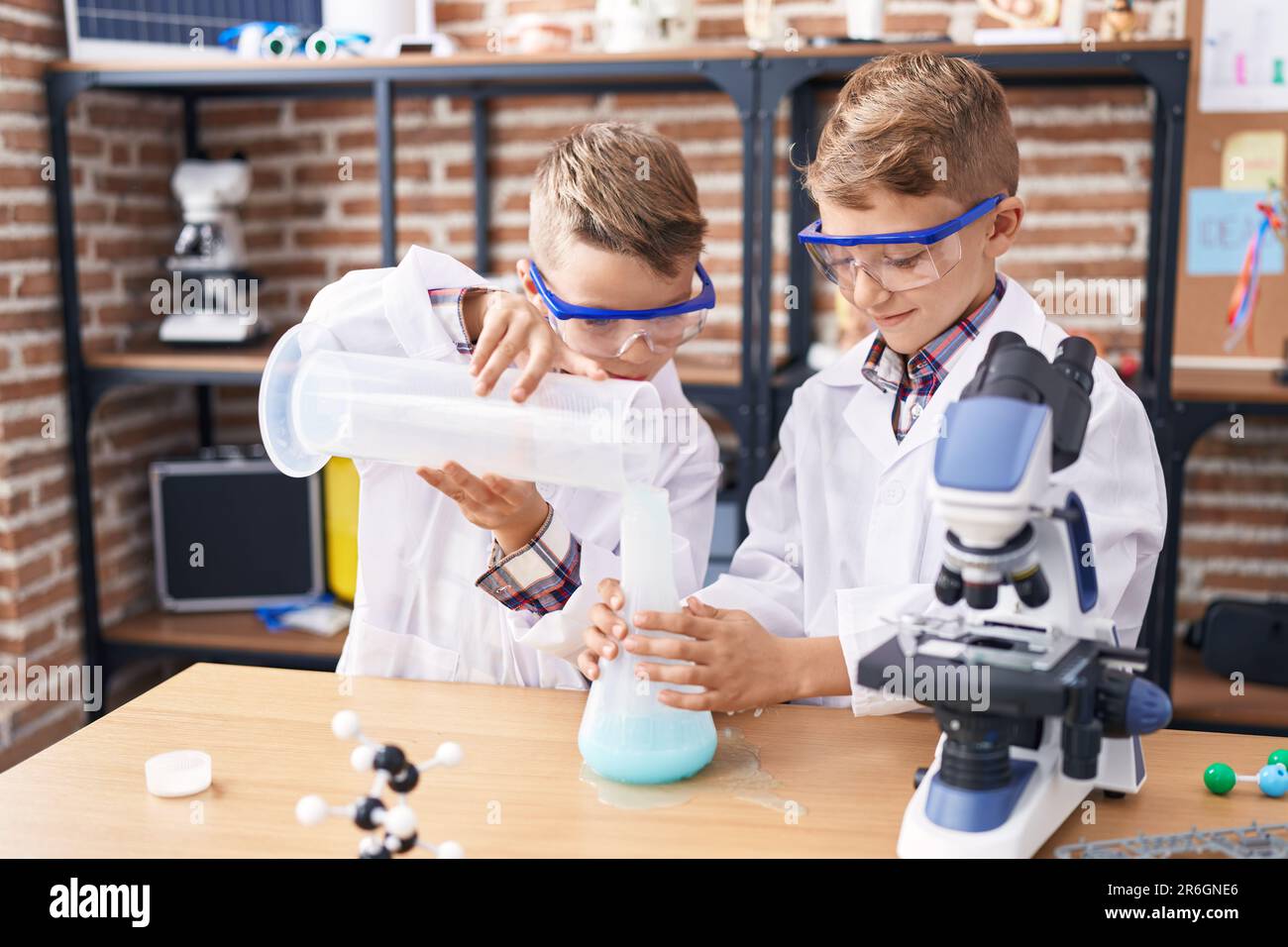 Adorable boys student pouring liquid on test tube at laboratory ...