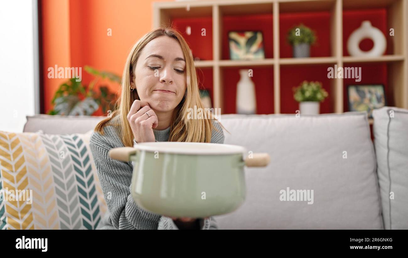 Young blonde woman holding cooking pot for water leak at home Stock ...