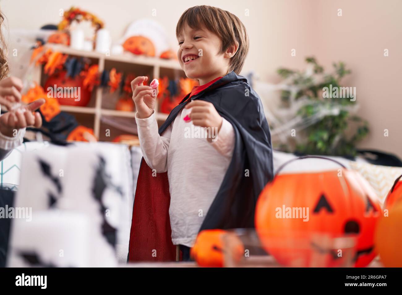 Adorable caucasian boy wearing vampire costume holding sweets at home ...