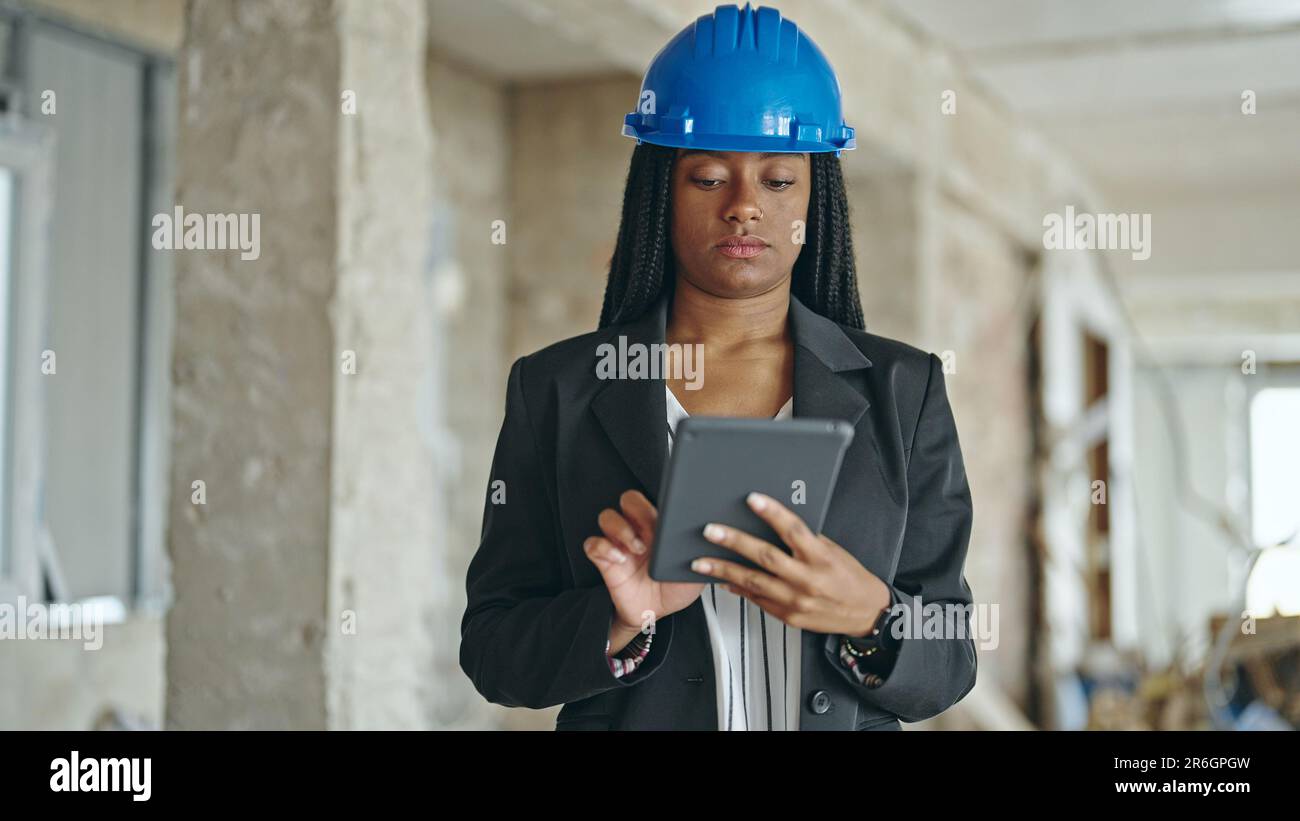 African american woman architect using touchpad walking at construction ...