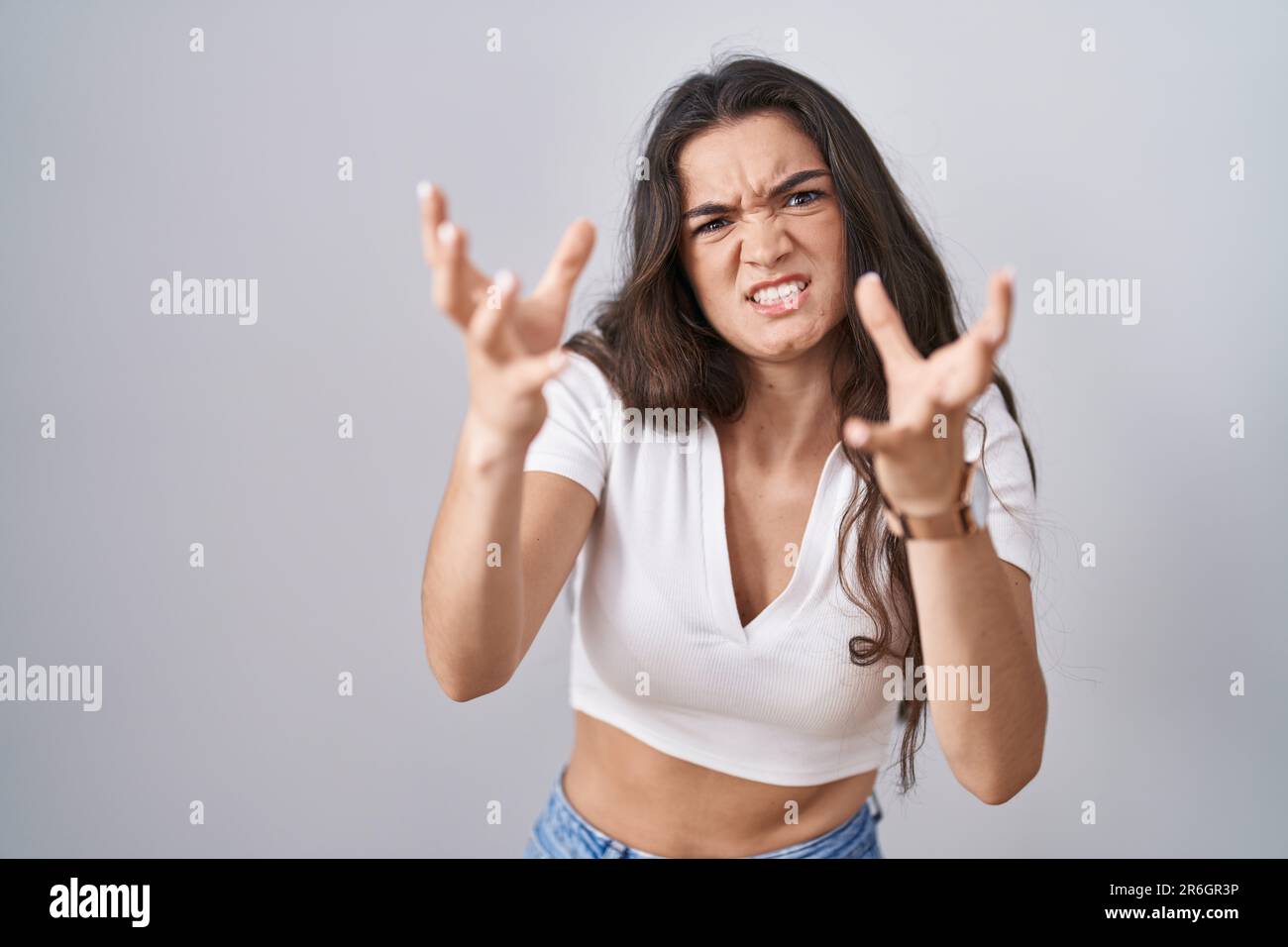 Young teenager girl standing over white background shouting frustrated ...