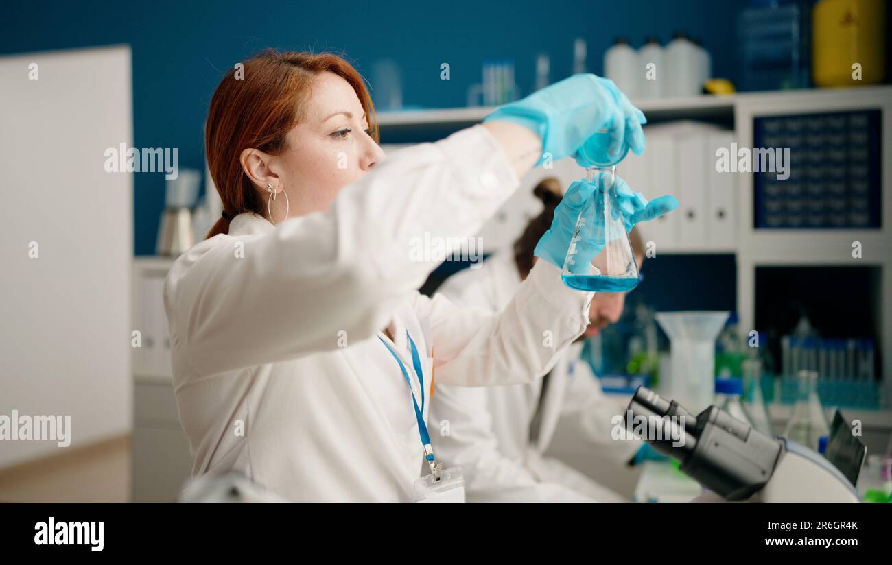 Man and woman wearing sciencist uniform using microscope at laboratory ...