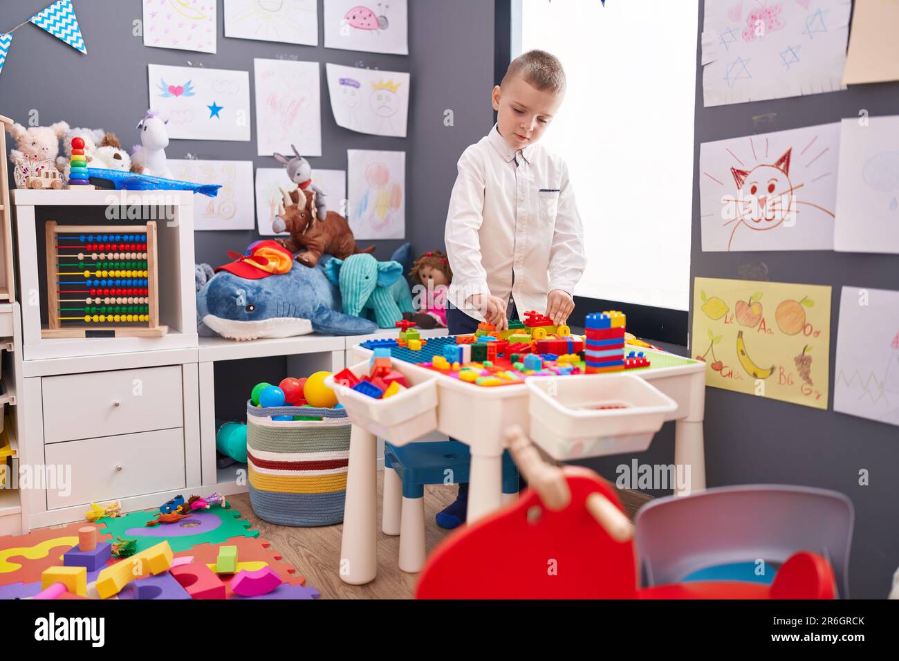 Adorable caucasian boy playing with construction blocks standing at ...