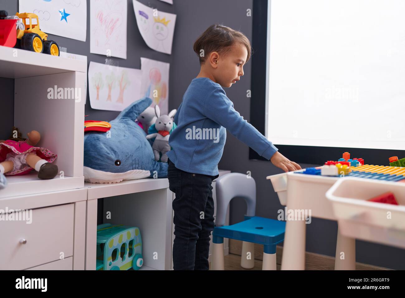 Adorable hispanic boy playing with construction blocks standing at ...