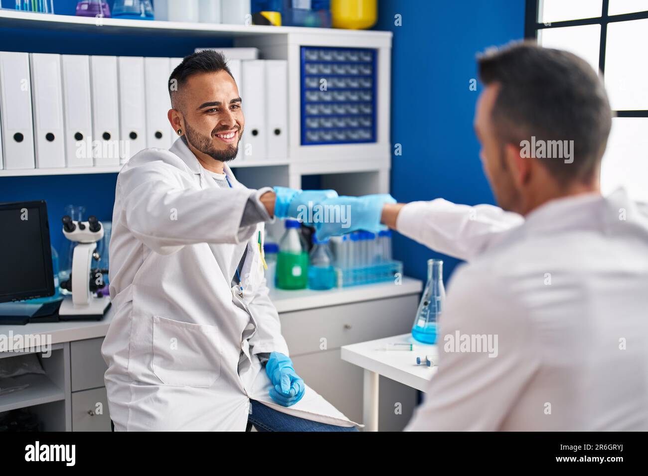 Two men scientists smiling confident bump fists at laboratory Stock Photo - Alamy