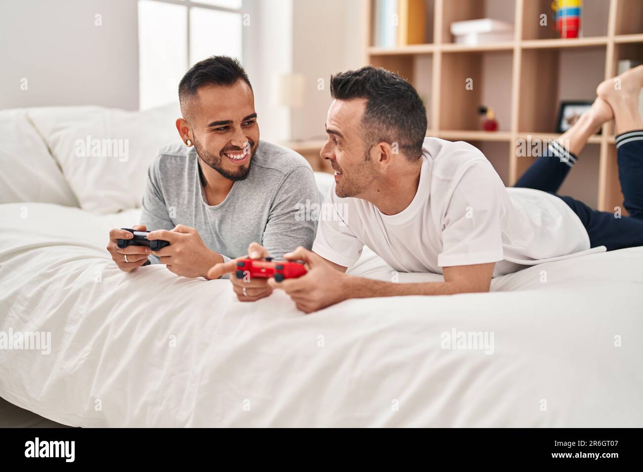 Two men couple playing video game lying on bed at bedroom Stock Photo ...