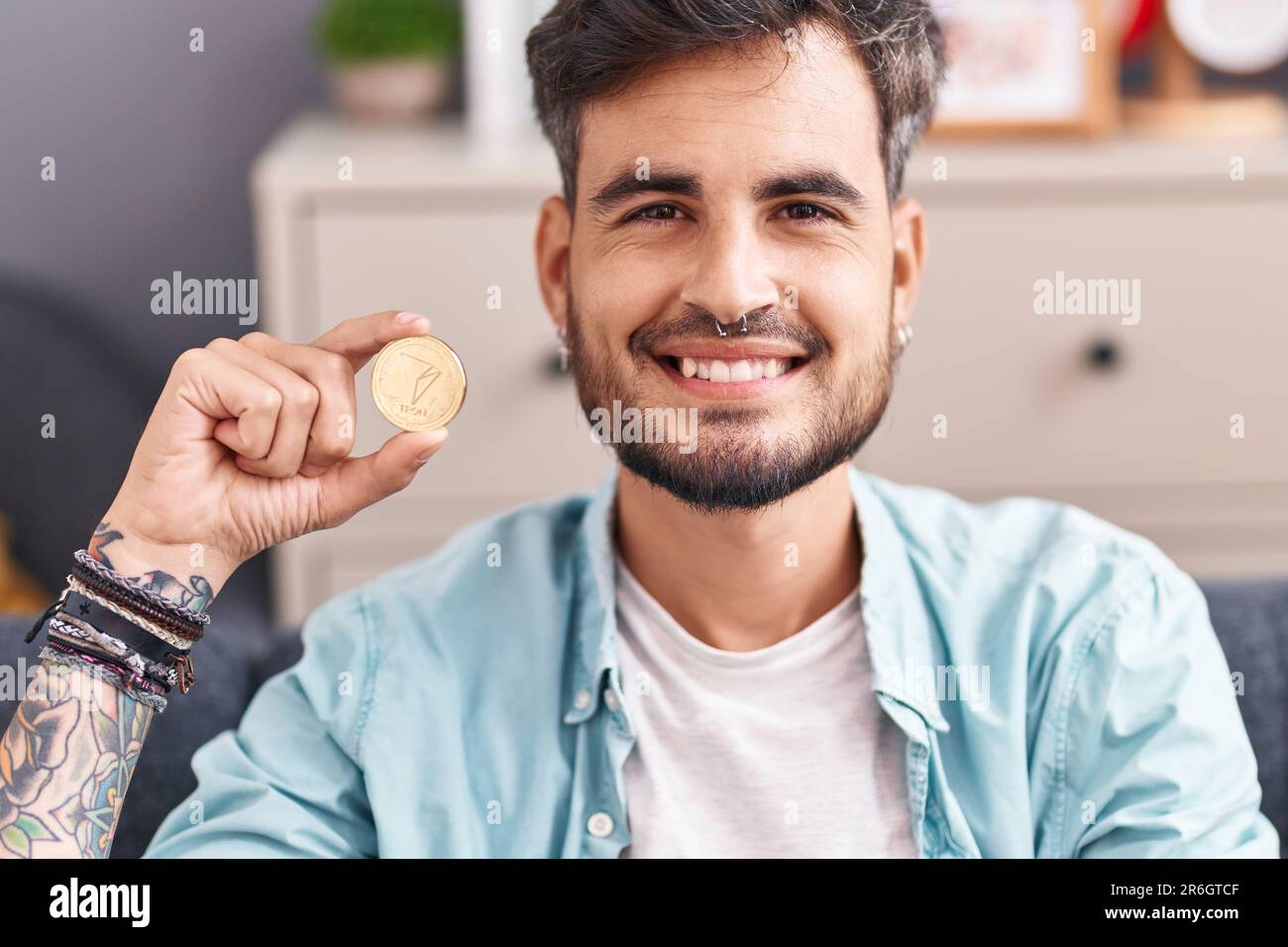 Young hispanic man with tattoos holding tron cryptocurrency coin ...