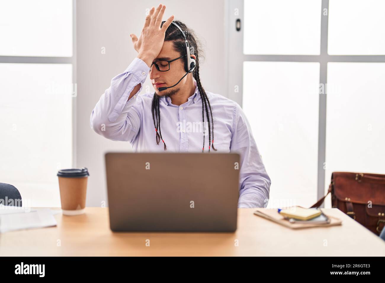 Hispanic man with long hair working using computer laptop surprised ...