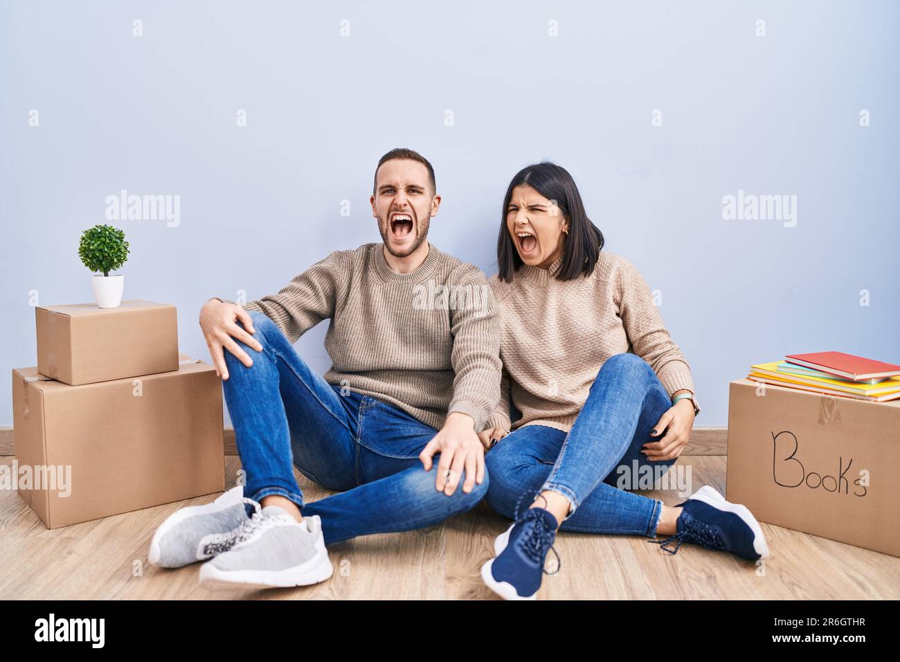 Young couple moving to a new home angry and mad screaming frustrated ...