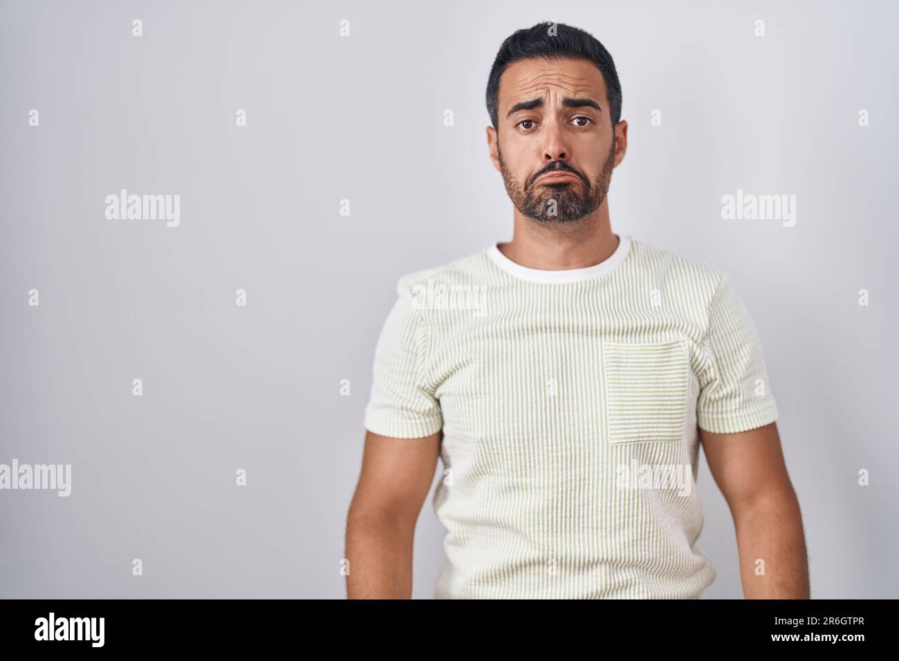 Hispanic man with beard standing over isolated background depressed and ...