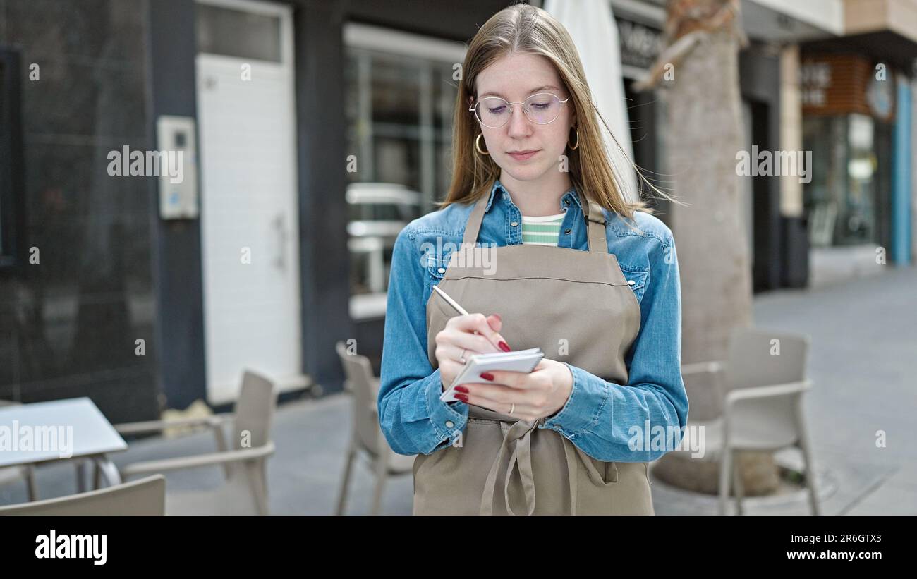 Young blonde woman waitress taking notes at coffee shop terrace Stock ...