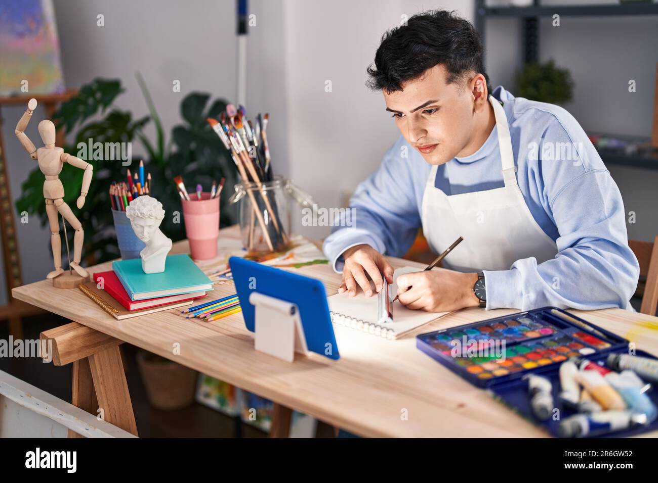 Young non binary man artist using touchpad drawing on notebook at art ...