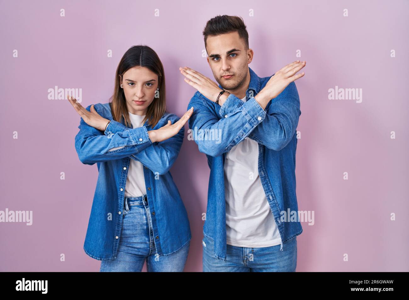 Young hispanic couple standing over pink background rejection ...