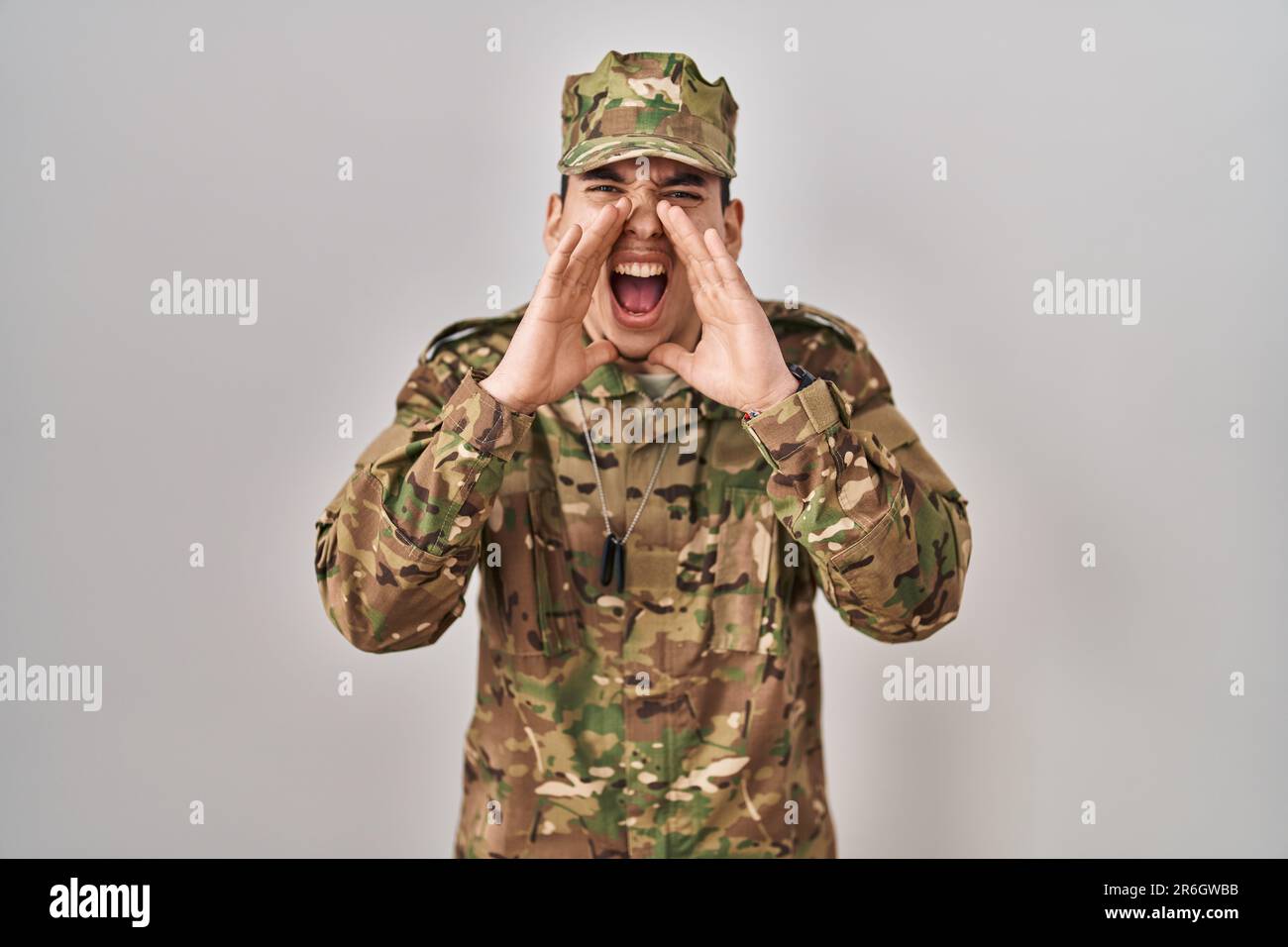 Young arab man wearing camouflage army uniform shouting angry out loud ...