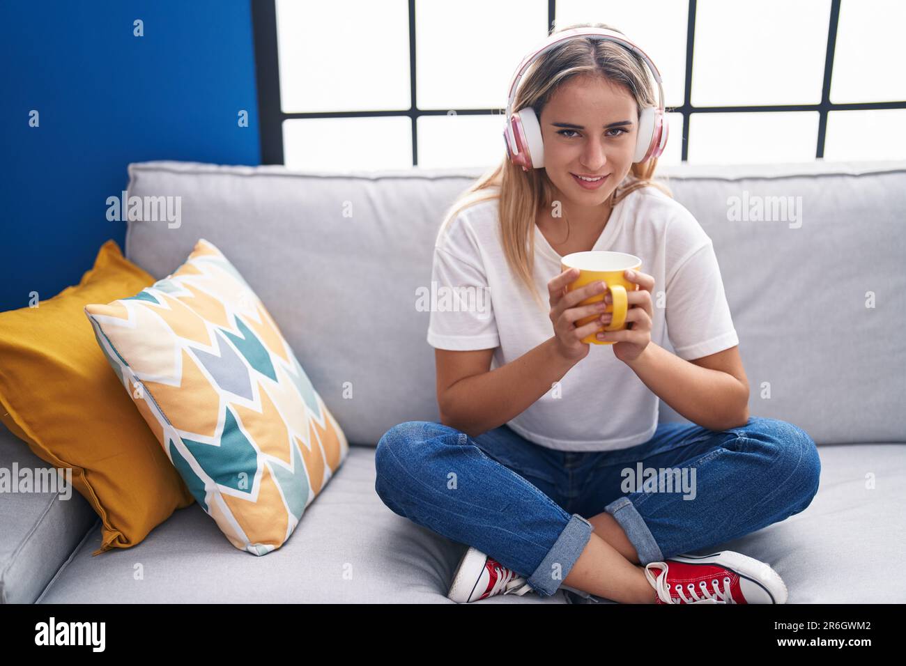 Young blonde woman listening to music drinking coffee at home Stock ...