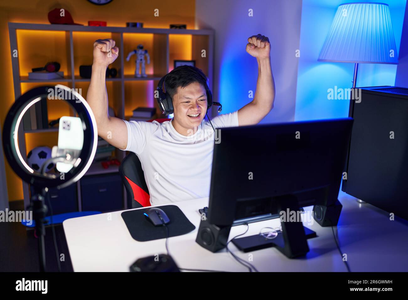 Young chinese man streamer playing video game with winner expression at ...