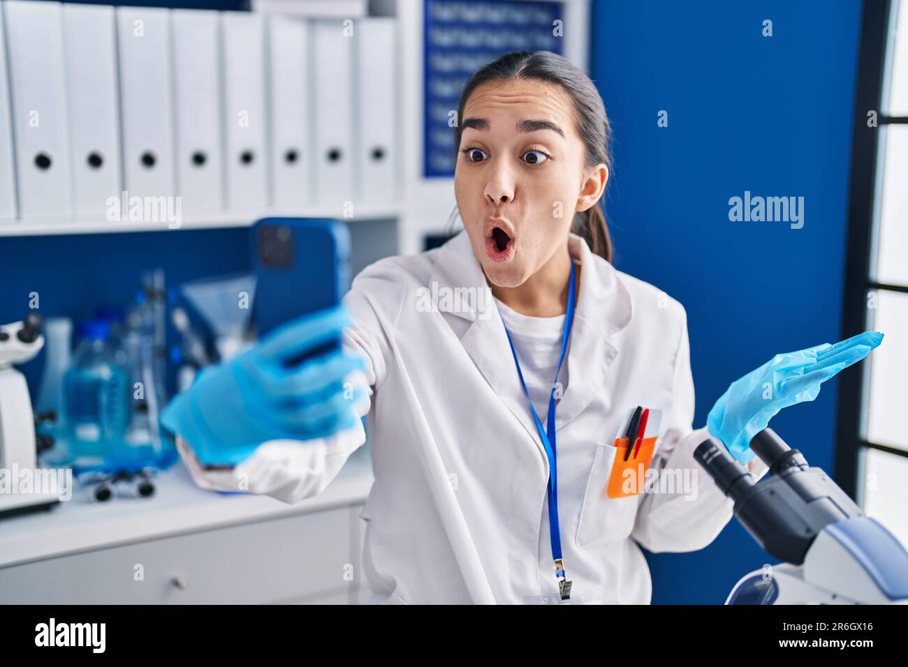 Young south asian woman working at scientist laboratory with smartphone ...