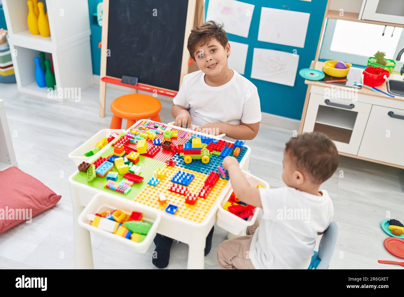 Adorable boys playing with construction blocks sitting on table at ...