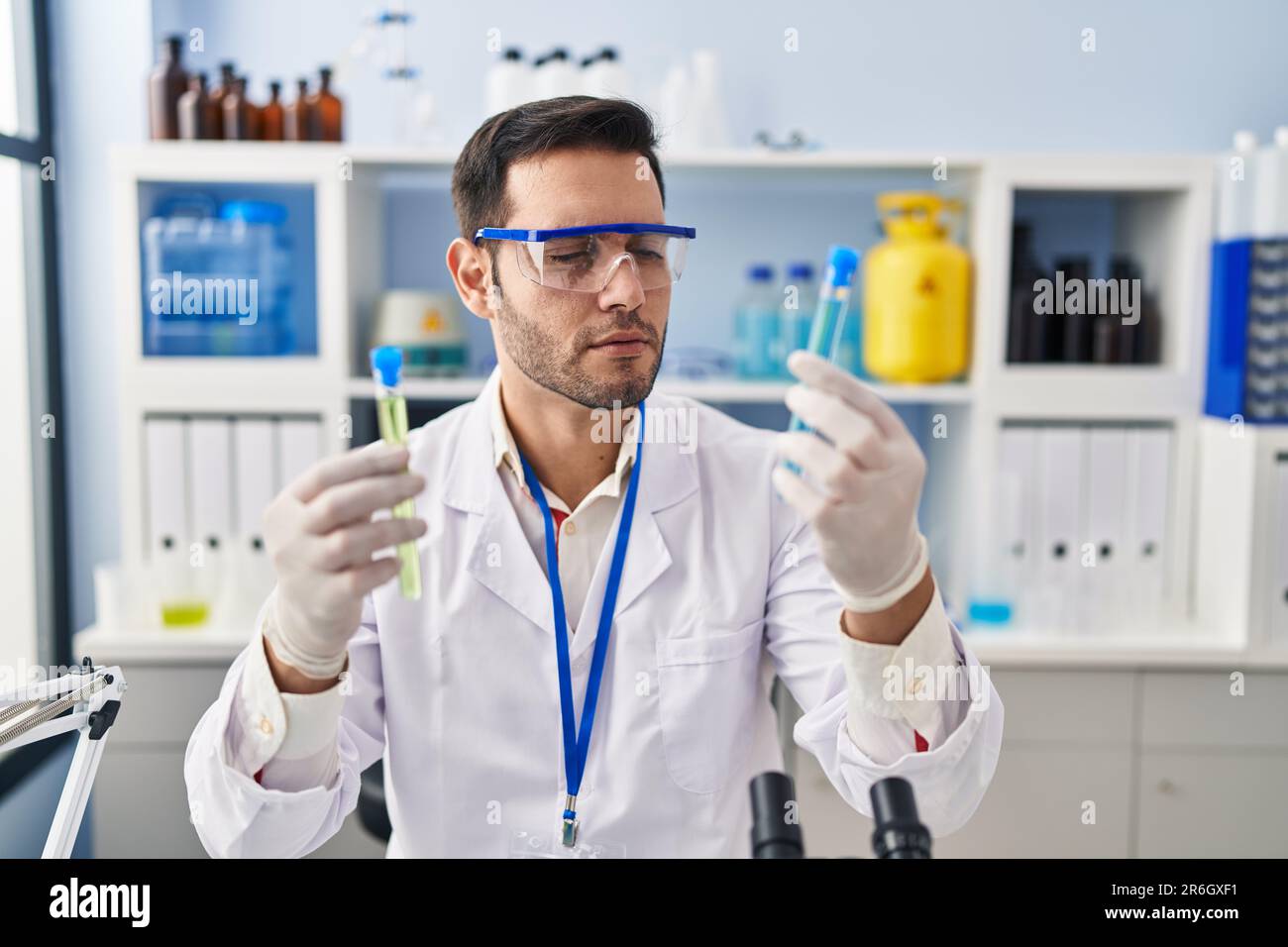 Young hispanic man scientist holding test tubes at laboratory Stock ...