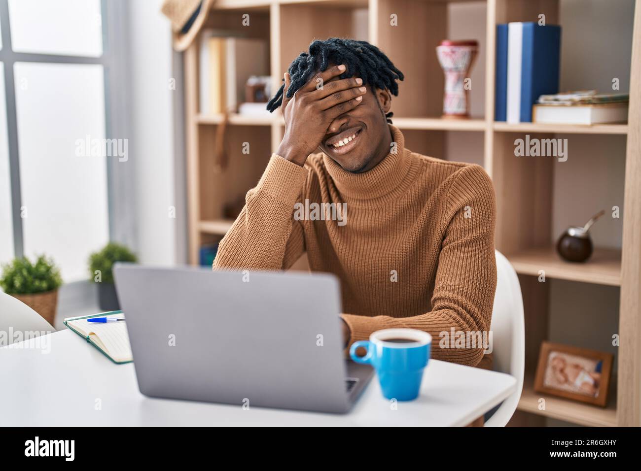 Young african man with dreadlocks working using computer laptop smiling ...