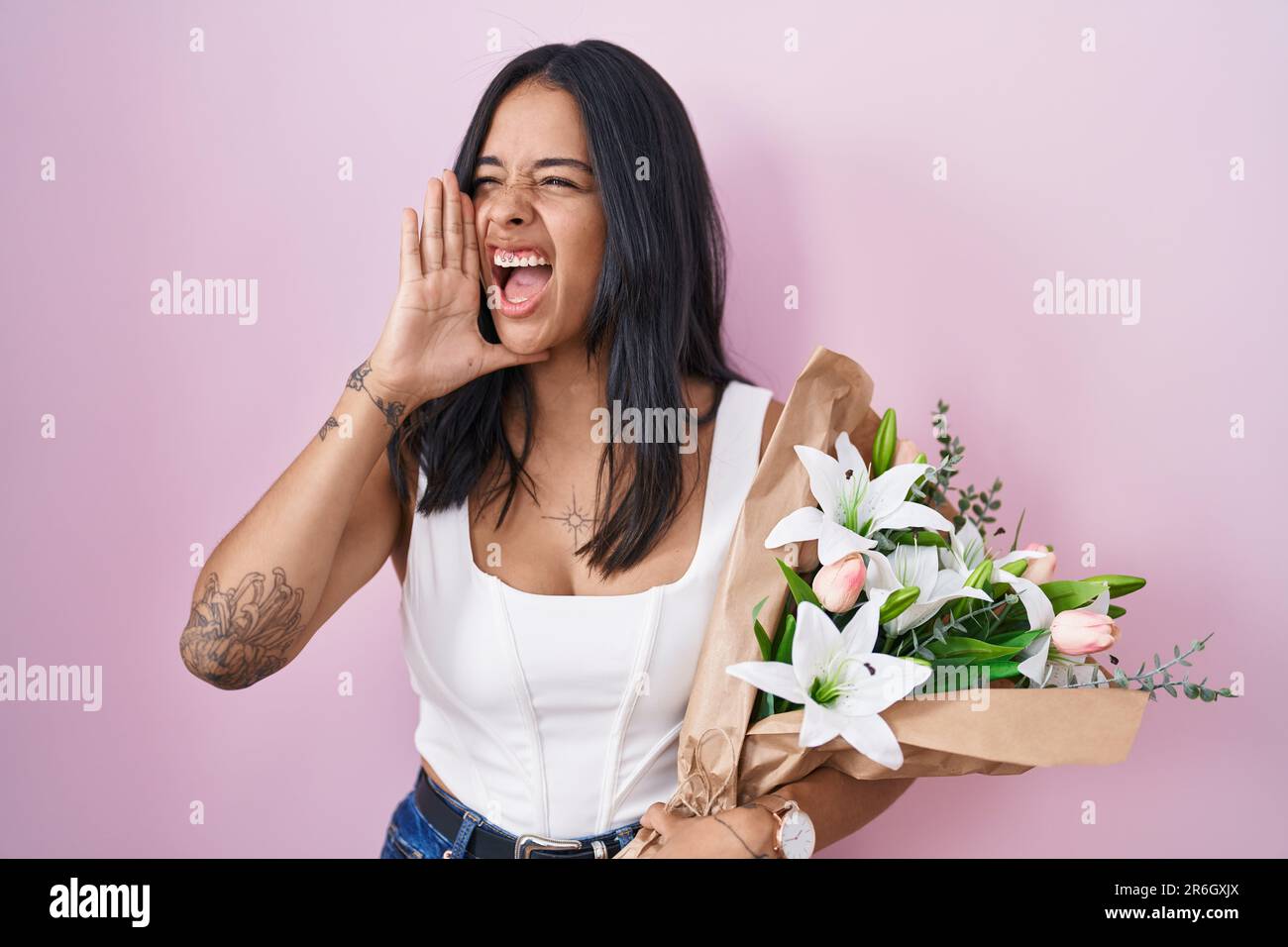 Brunette woman holding bouquet of white flowers shouting and screaming ...