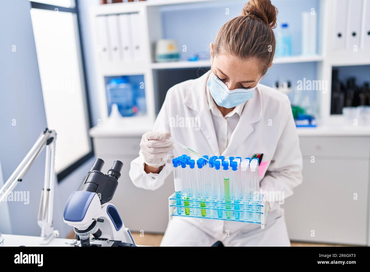 Young woman scientist pouring liquid on test tubes at laboratory Stock ...