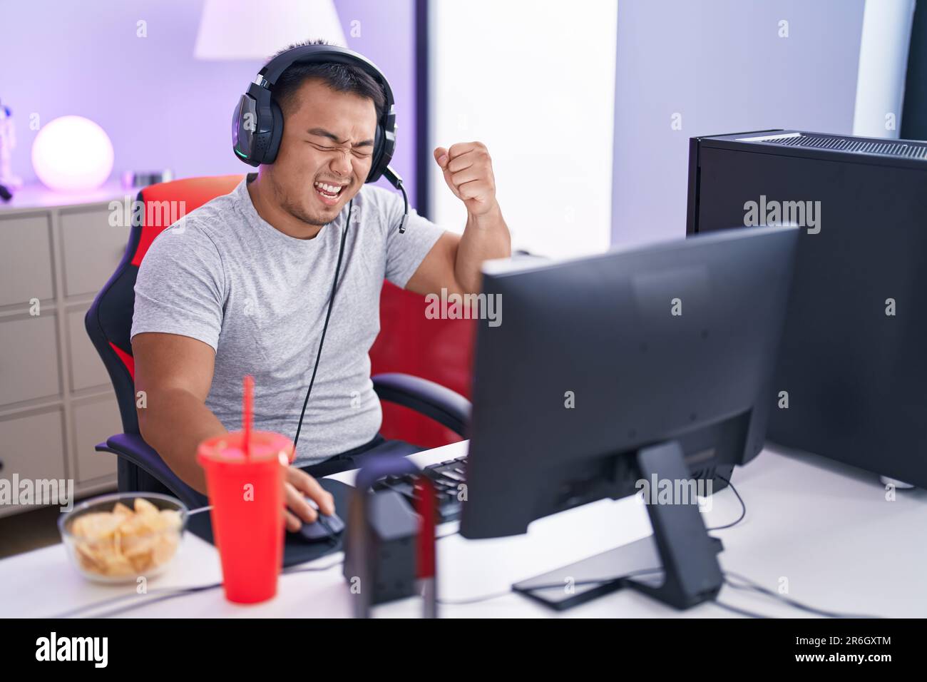 Young chinese man streamer playing video game with winner expression at ...