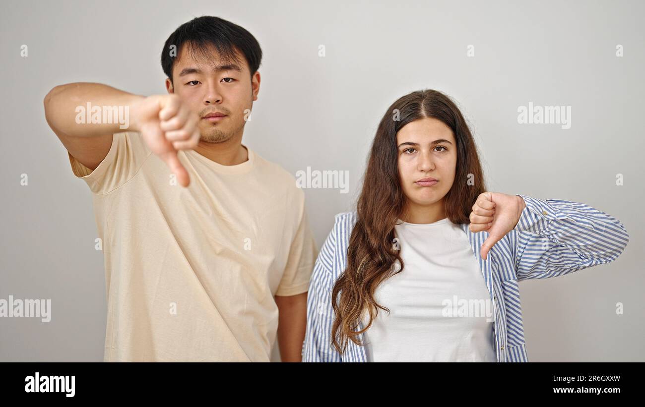 Man and woman couple standing together doing thumbs down gesture over ...