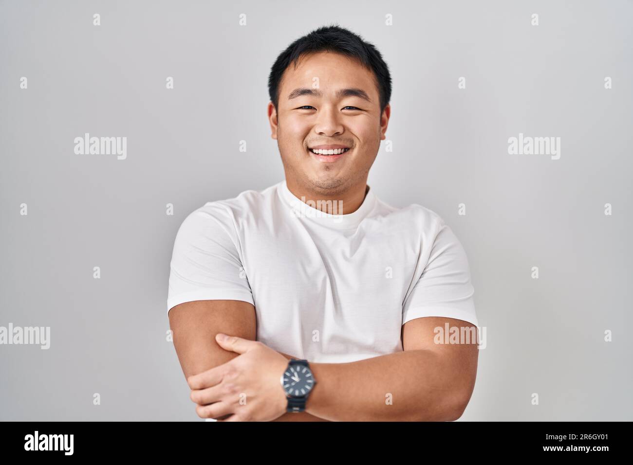 Young chinese man standing over white background happy face smiling ...