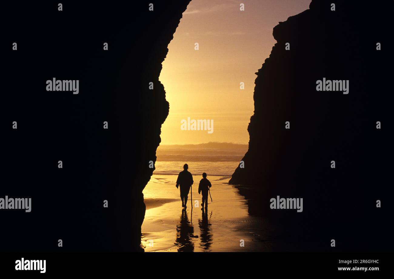 Mother and daughter silhouetted walking through rock formation along ...