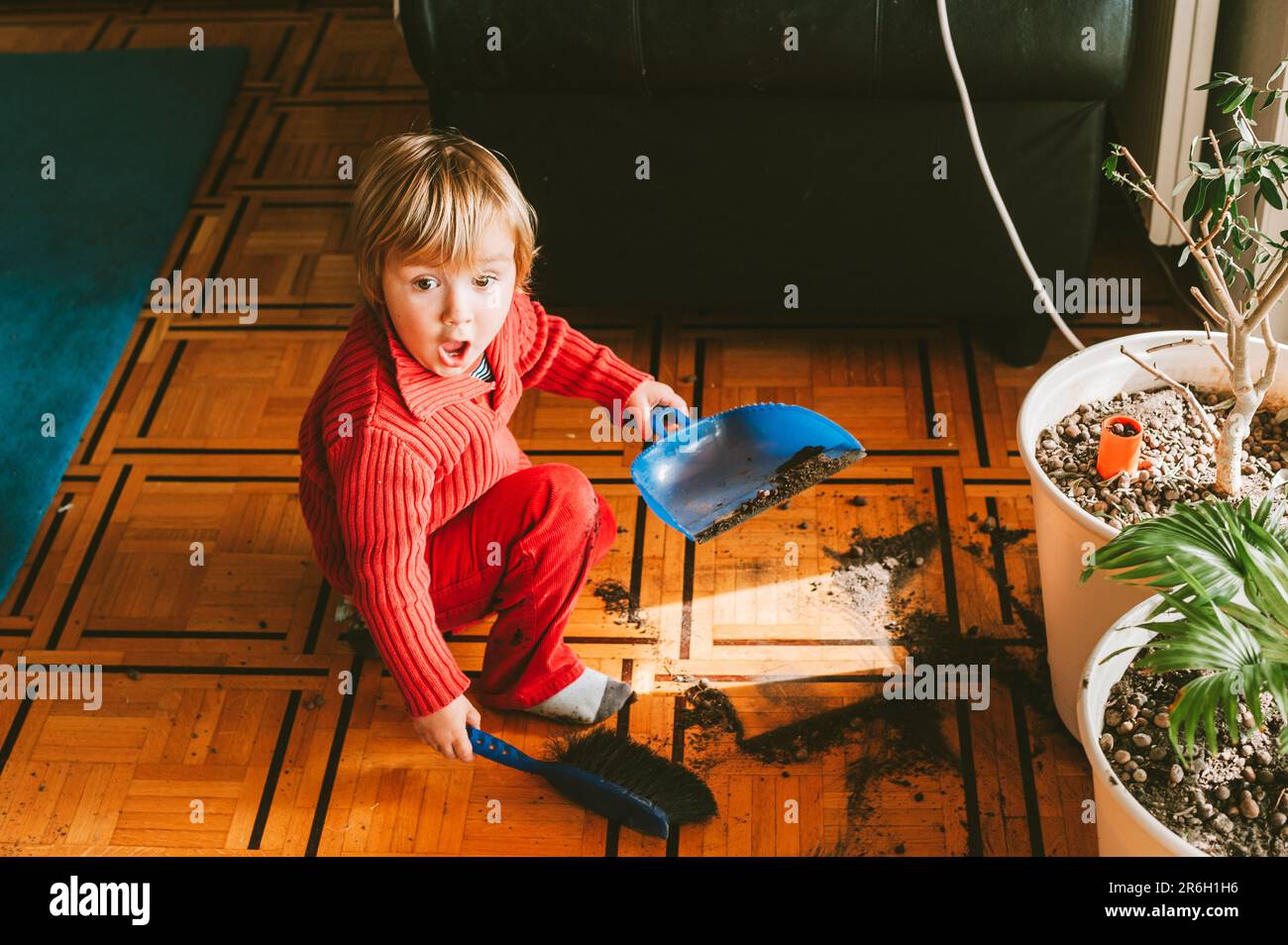 Very messy baby with funny facial expression cleaning plant soil from ...