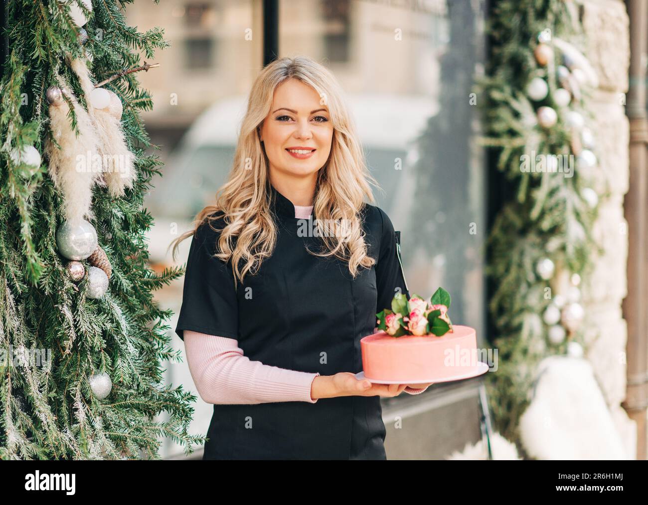 Portrait of cheerful baker woman standing next to facade of Tea Room ...