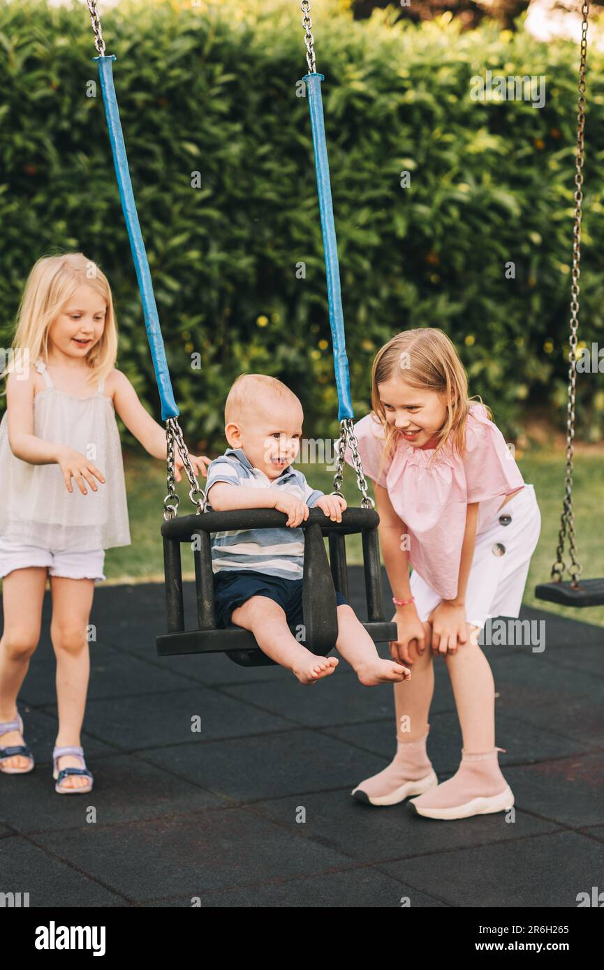 Family of 3 kids playing together outside, big sisters taking care of ...