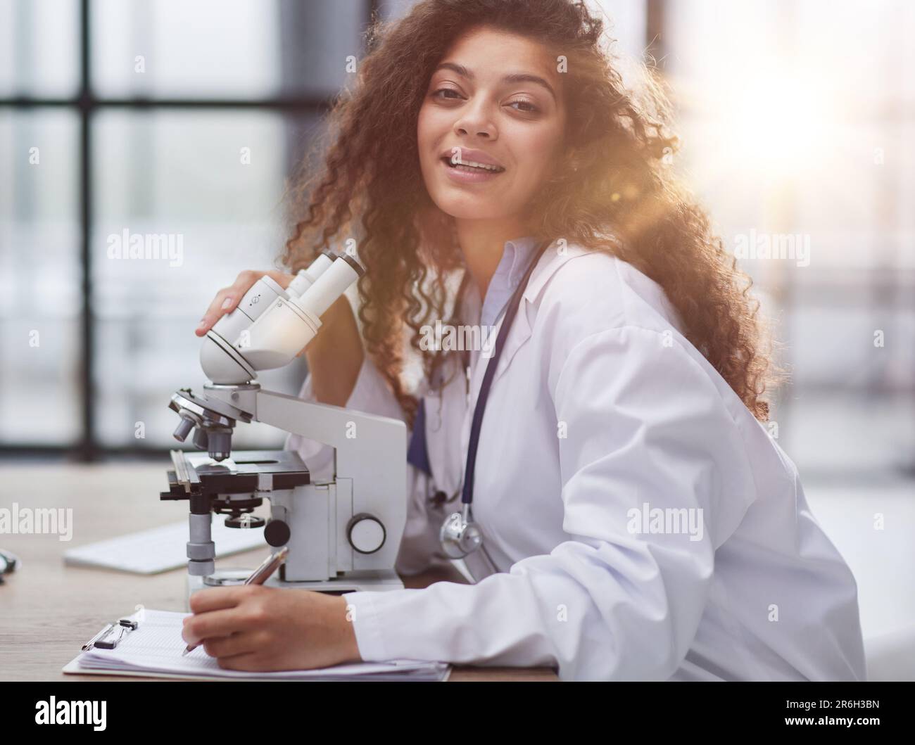 Attractive female scientist looking through a microscope Stock Photo ...