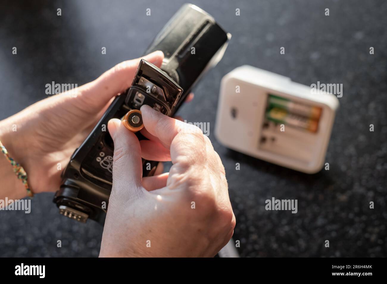A woman inserts batteries into a camera flash to take pictures Stock ...