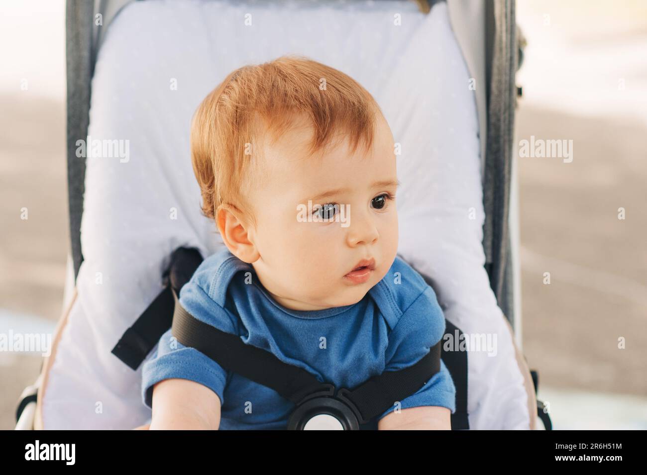 Outdoor close up portrait of adorable redheaded baby boy sitting in a ...