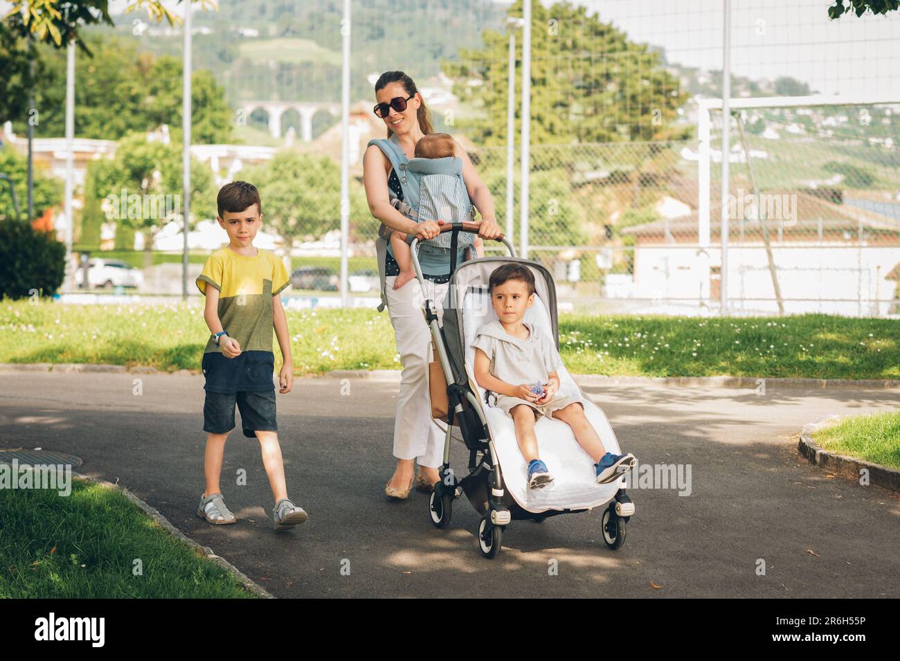 Young mother with three kids walking outside on a nice sunny day ...