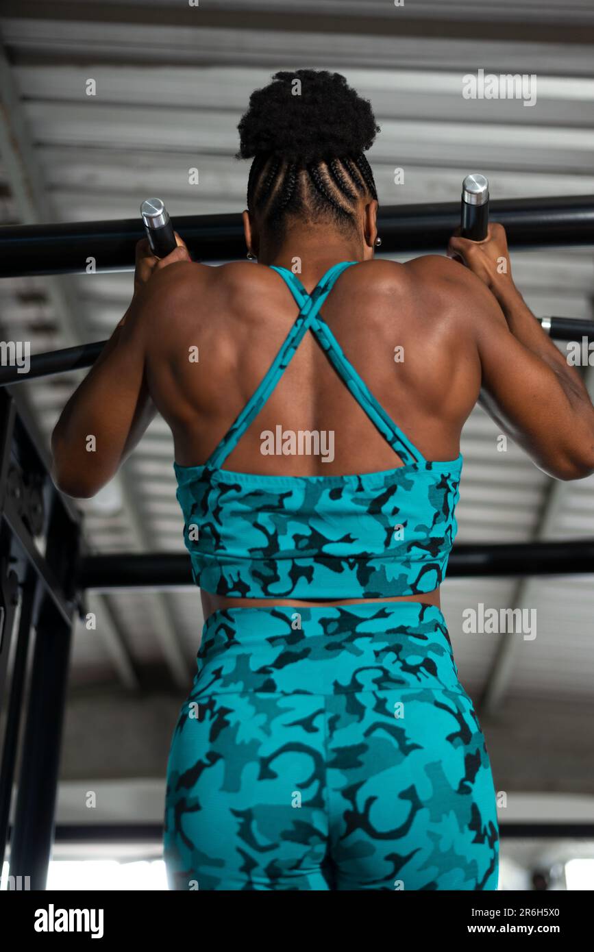 A female athlete is performing an overhead pull-up on a pair of ...
