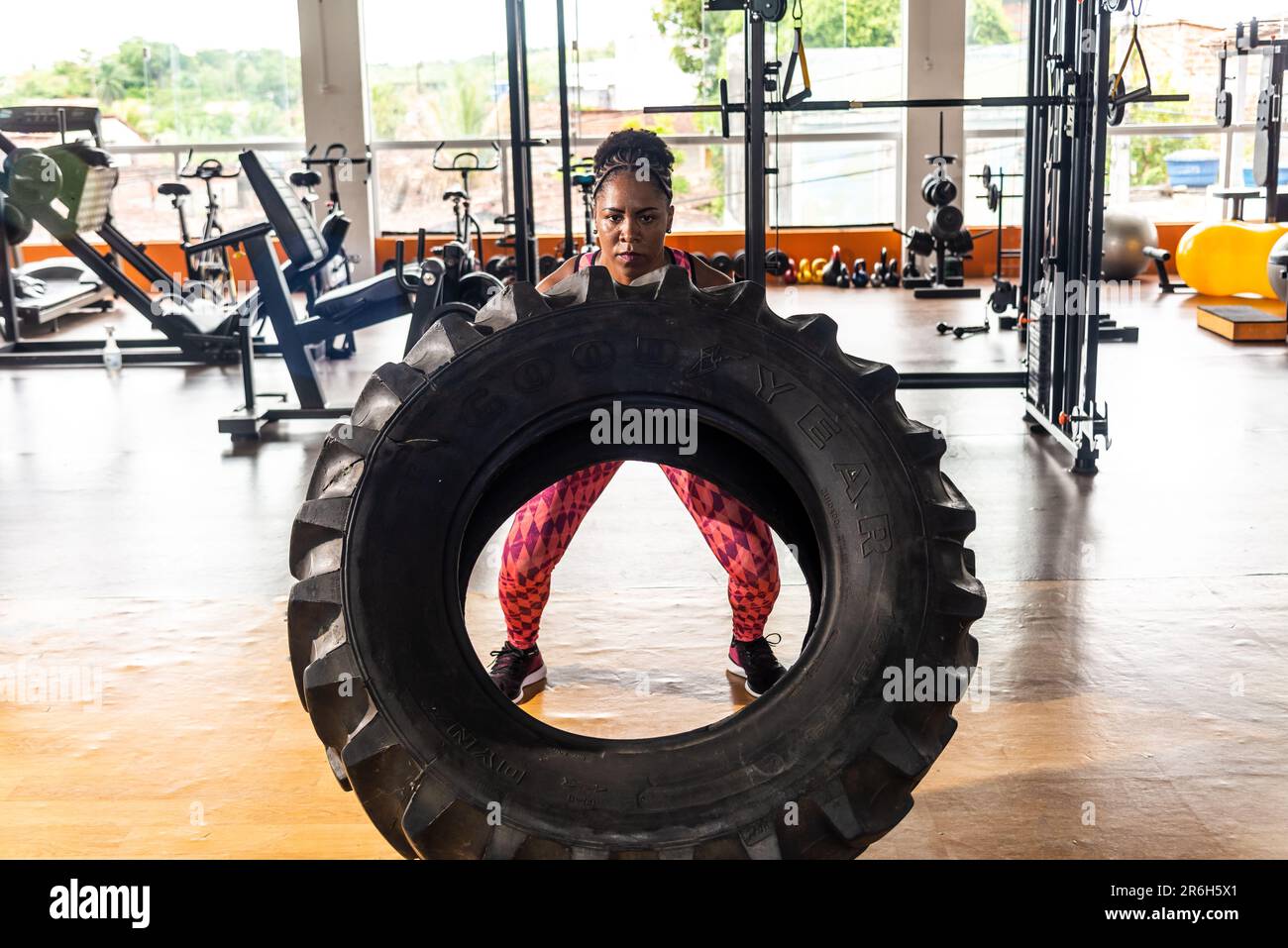 A woman in fitness gear performing a strength exercise, pulling a tire ...
