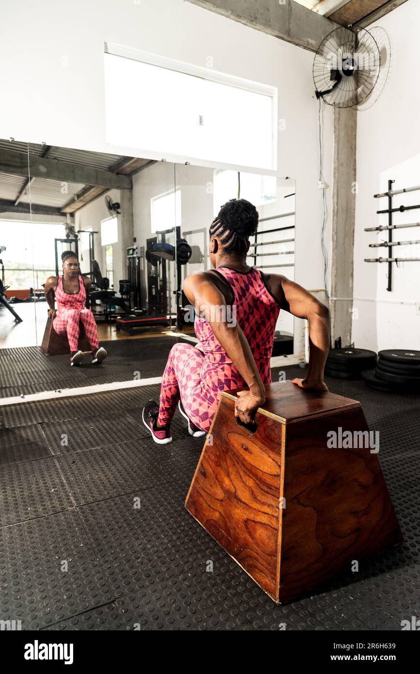 A cheerful female athlete is performing a workout routine while sitting ...