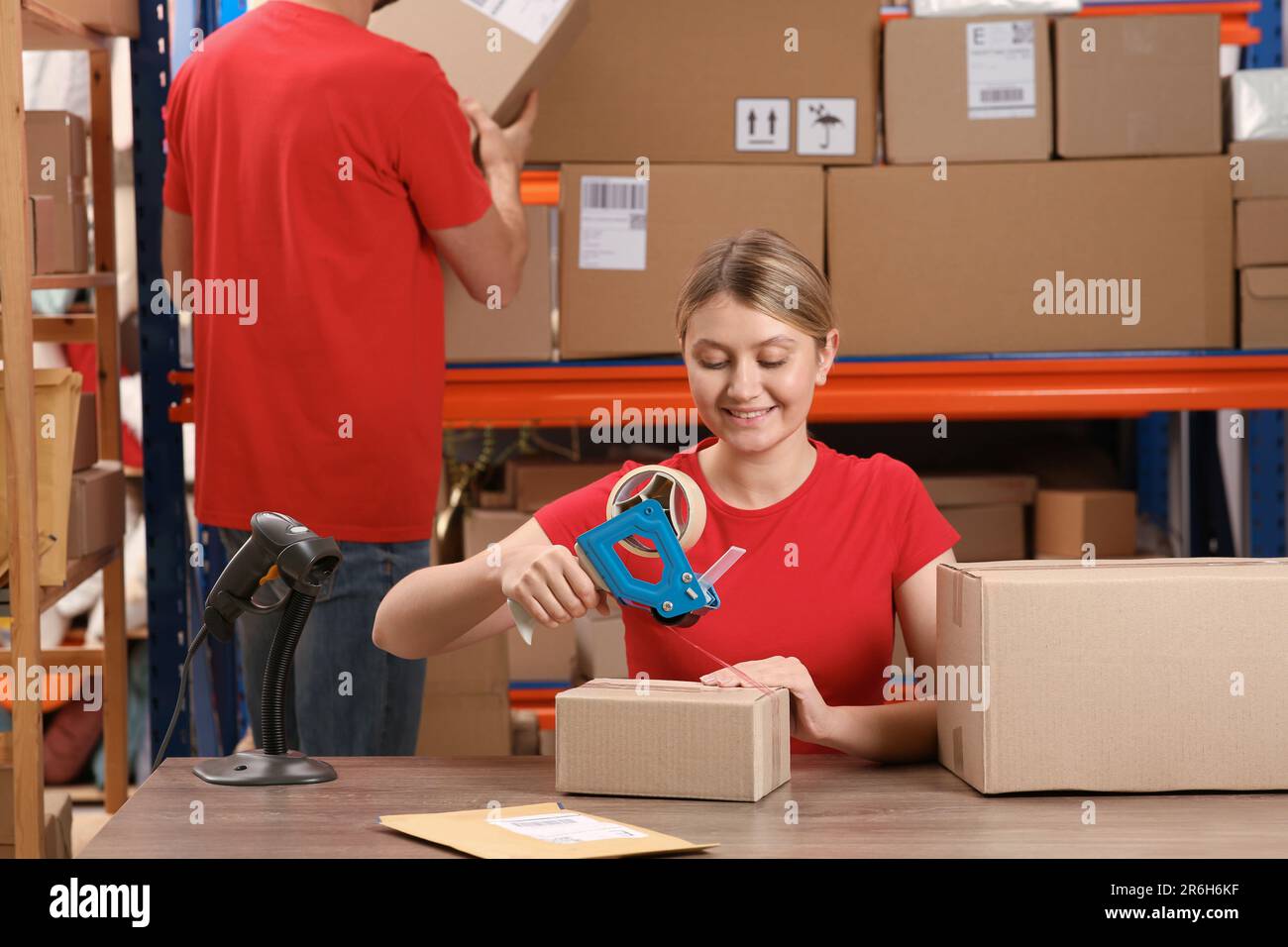 Post office worker packing parcel at counter indoors Stock Photo - Alamy