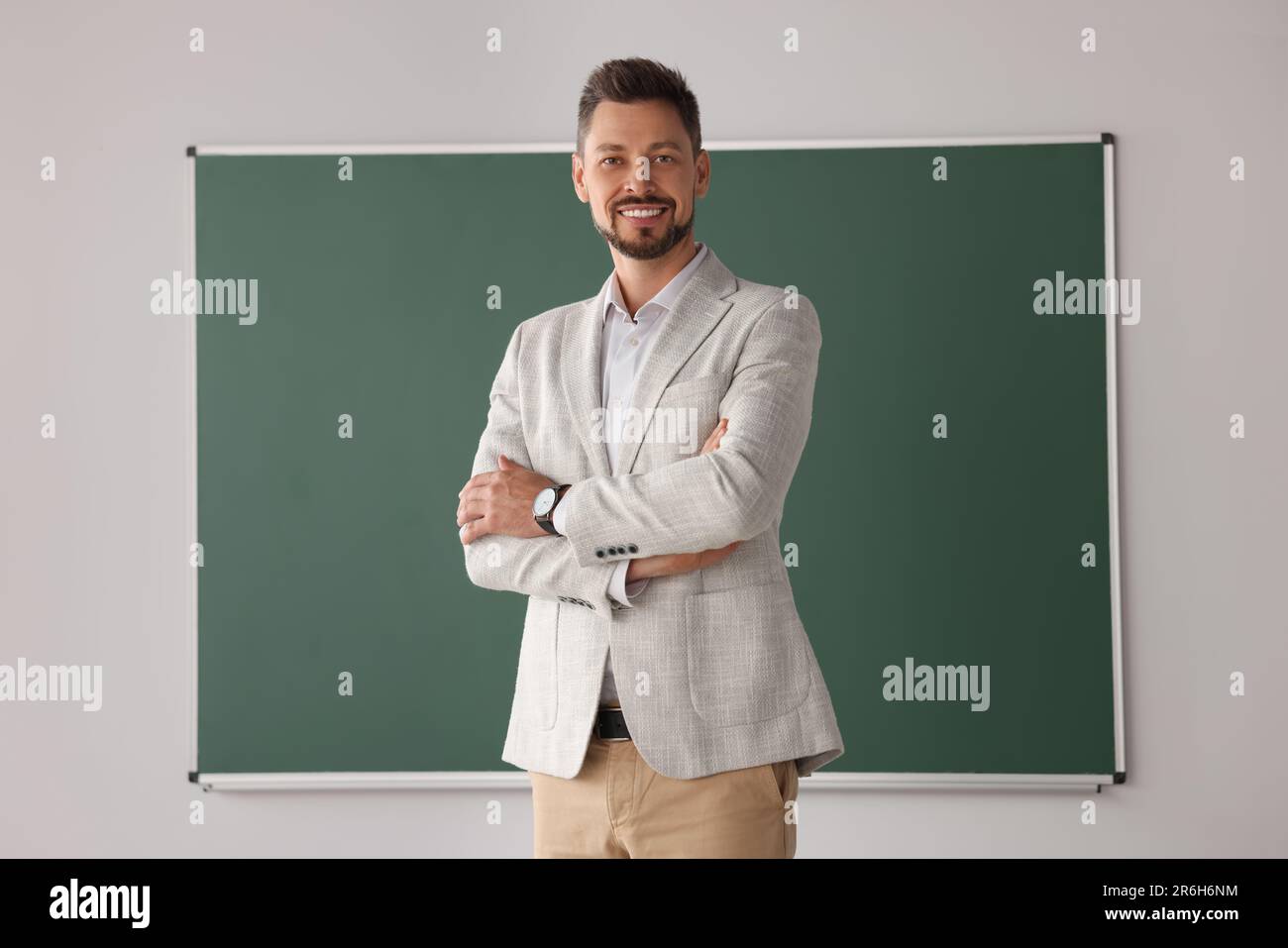Happy teacher standing at blackboard in classroom Stock Photo - Alamy